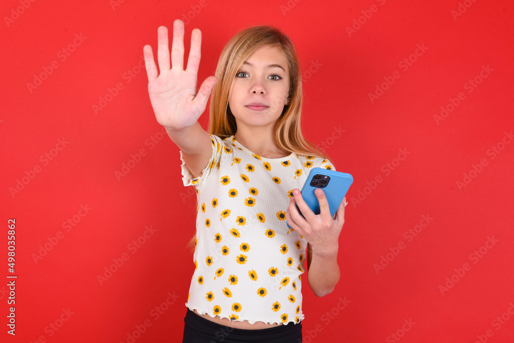 blonde little kid girl wearing daisy t-shirt over red background using ...