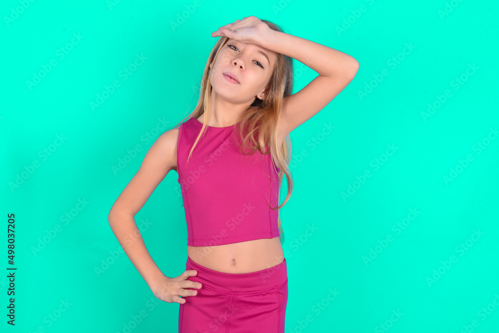 blonde little kid girl wearing pink sport clothes over green wall ...
