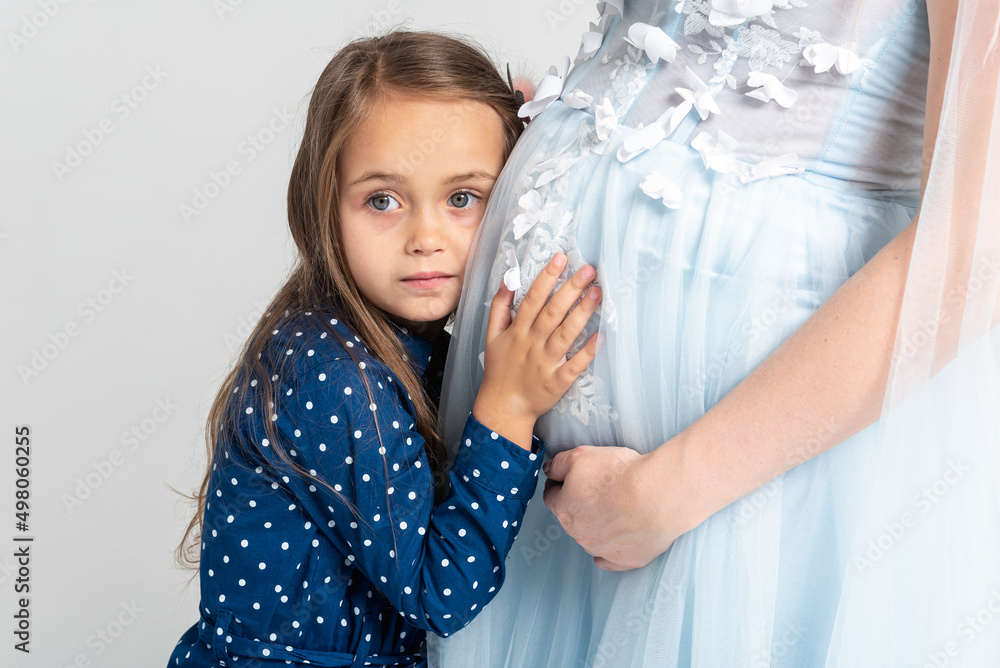 the little girl leaned against her mother who is pregnant, tenderly ...