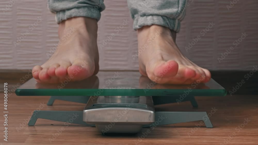 Women's feet stand on the scales and check their kilograms front view ...