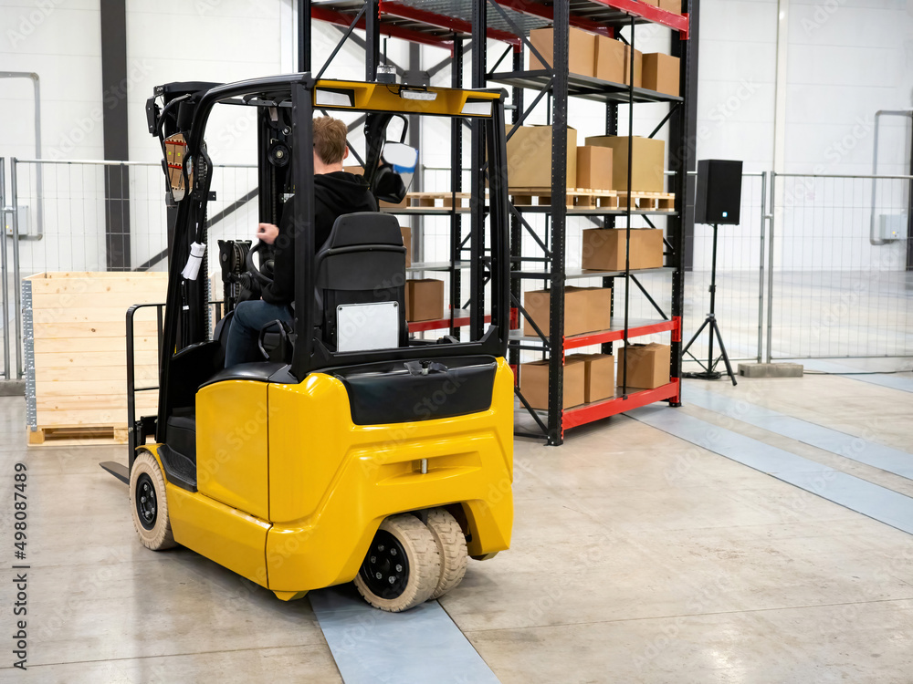 Man operates forklift. Forklift heading towards pallet rear view ...