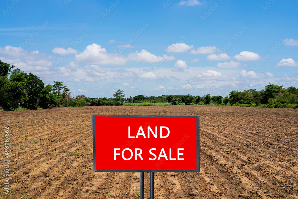 land for sale sign against trimmed lawn background. Empty dry cracked ...