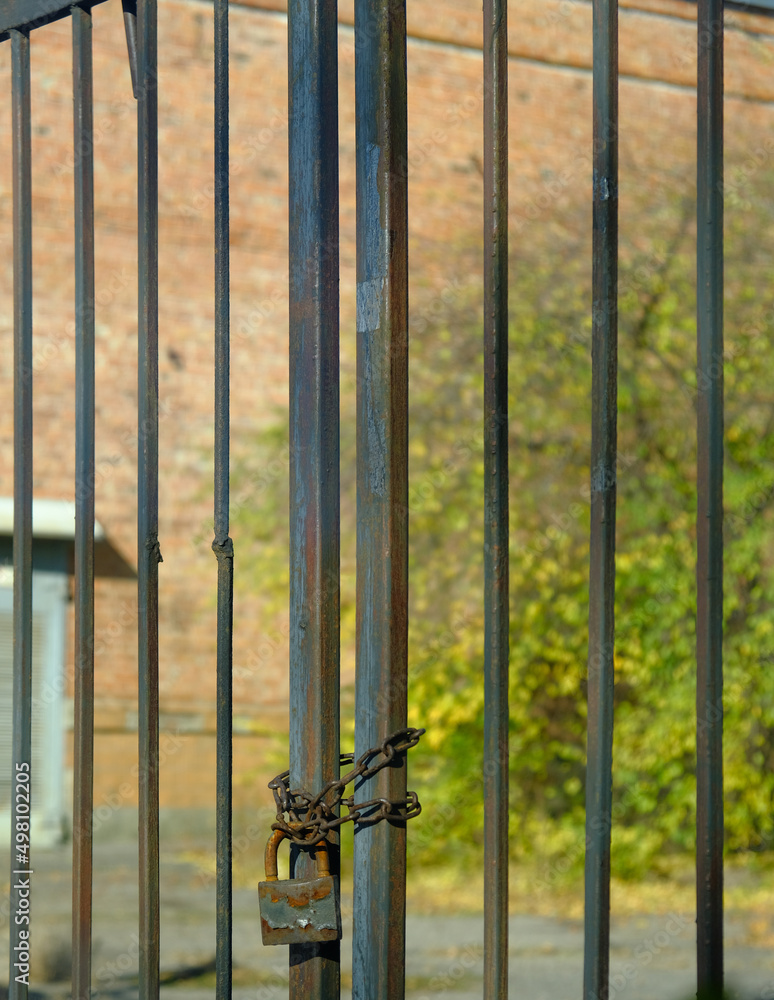 The old gates of the factory are locked with a rusty old chain around ...