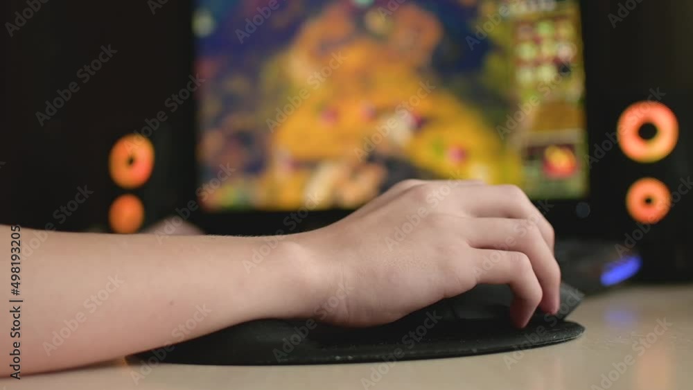 A teenage boy sitting at a table playing a computer game. The hand ...