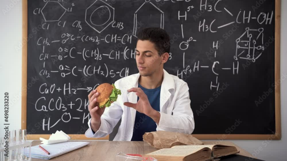 Young Arabic chemistry teacher holding a piece of hamburger. Student ...