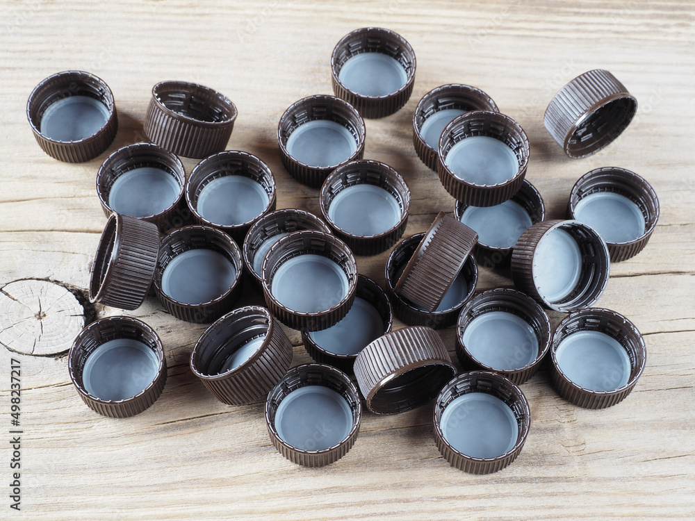 Pile of brown plastic bottle caps on a wooden table, close up, flat ...