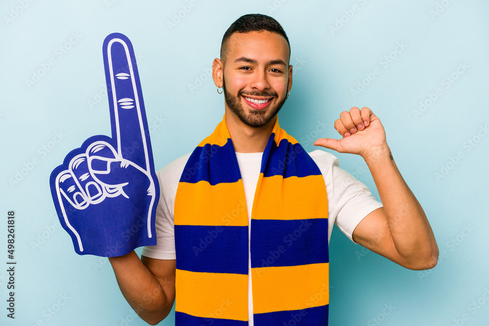 Young sports hispanic fan man isolated on blue background feels proud ...