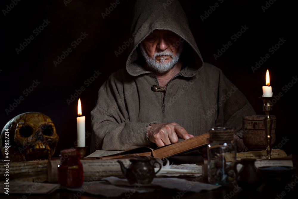 Old sorcerer studies magic book Stock Photo | Adobe Stock