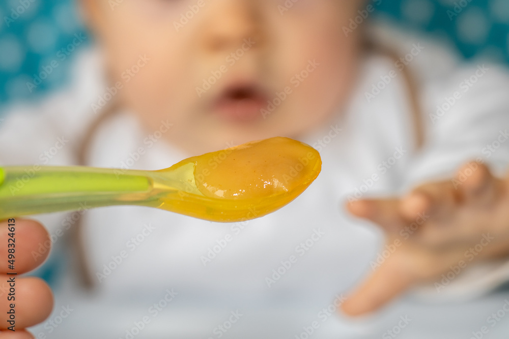 hungry cute little baby boy is sitting in feeding chair and eating ...