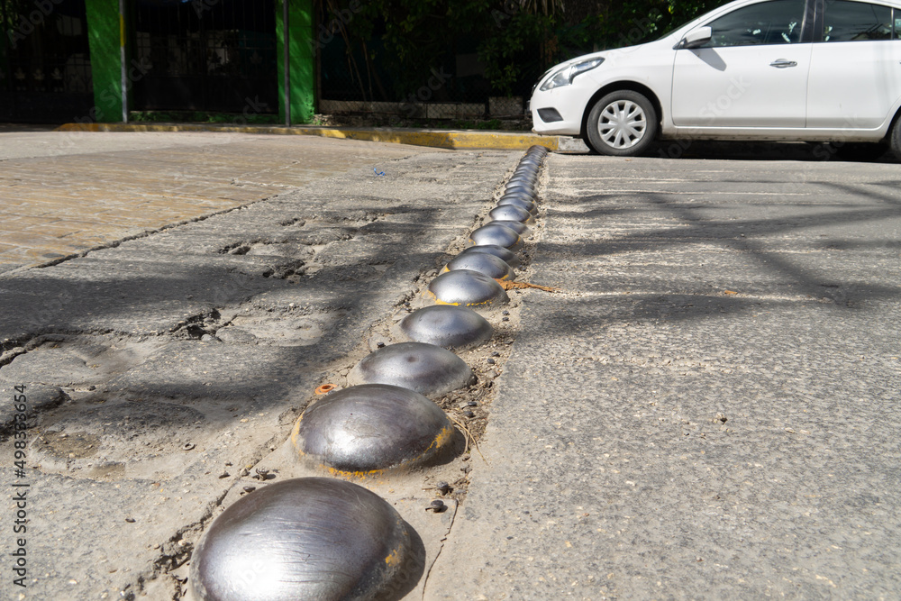 Speed bump on the road. A metal speed limiter, a blurred car is parked ...