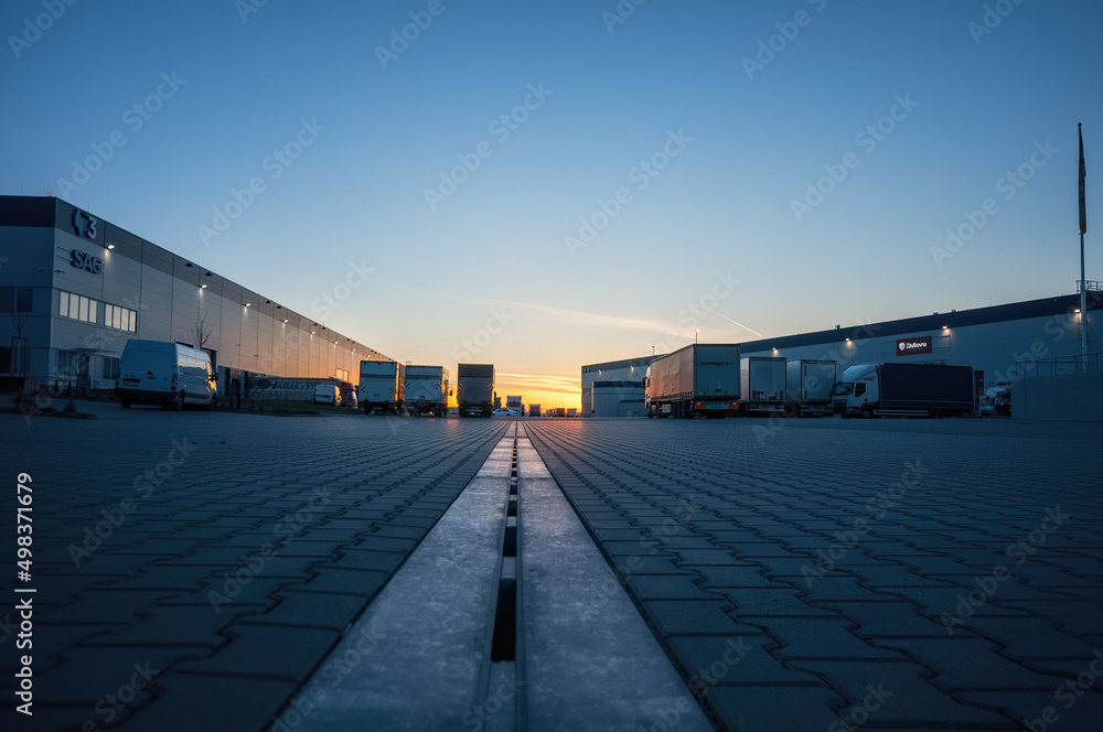 Logistics area with halls and trucks at sunset. Transport and storage ...