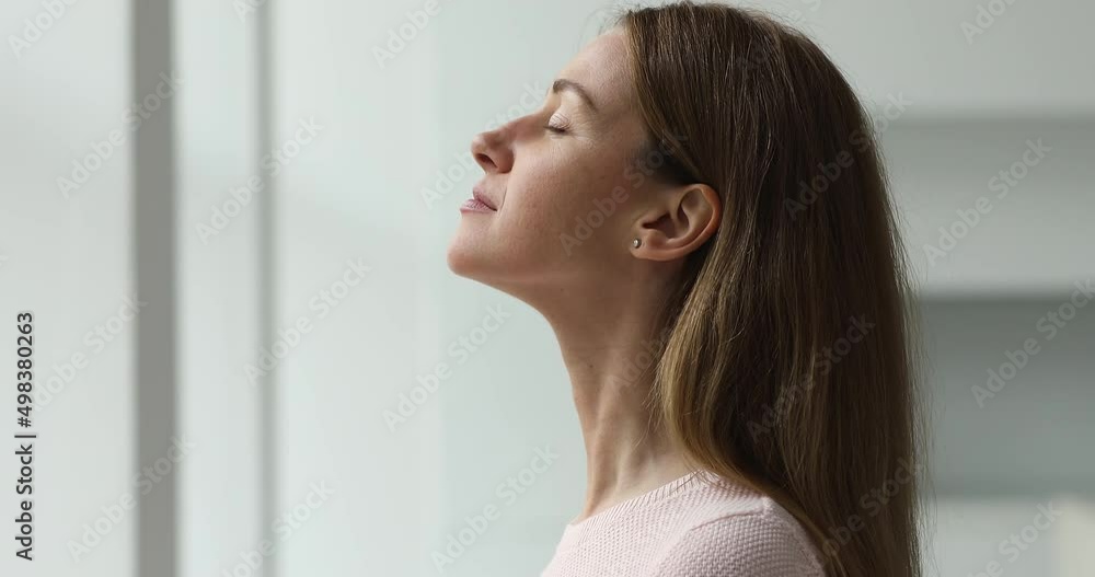 Calm young woman taking deep breath of fresh air meditating with eyes ...