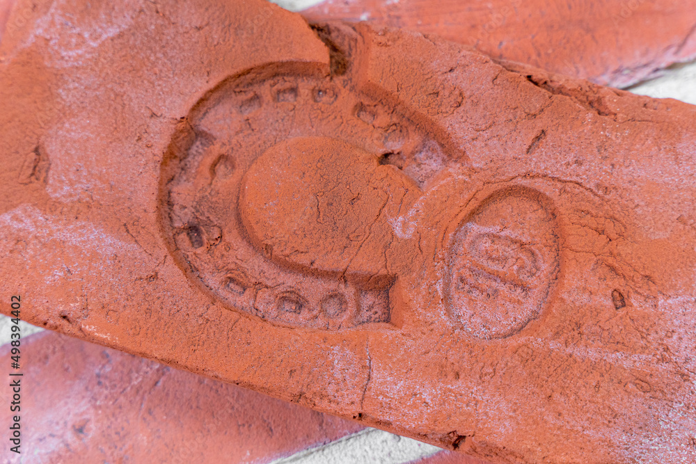 Red plaster decorative tile based on casts of old bricks with horseshoe ...