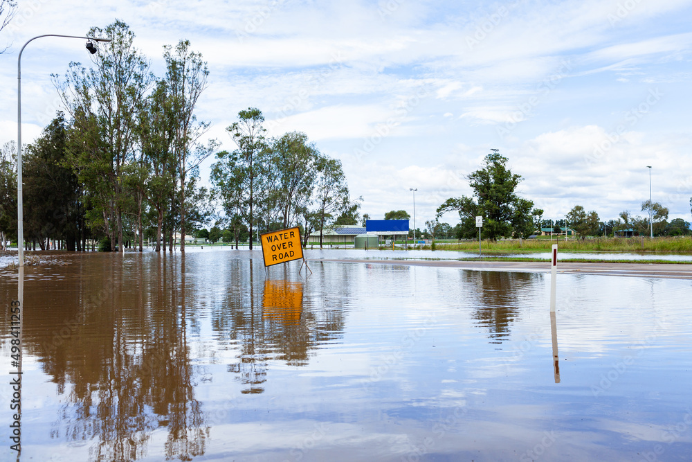 Floodwater rising over water over road sign on highway Stock Photo ...