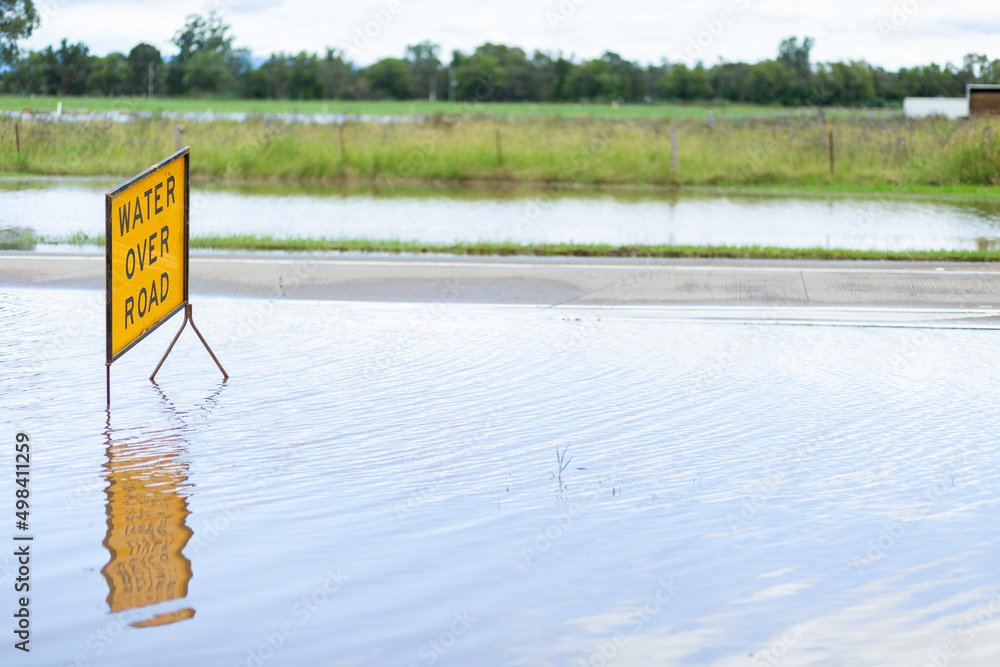 Floodwater rising over water over road sign on highway Stock Photo ...