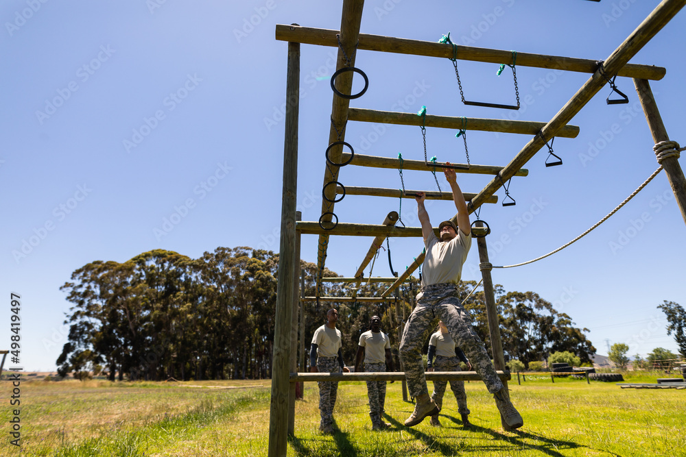Caucasian male soldier climbing monkey bars during obstacle course at ...