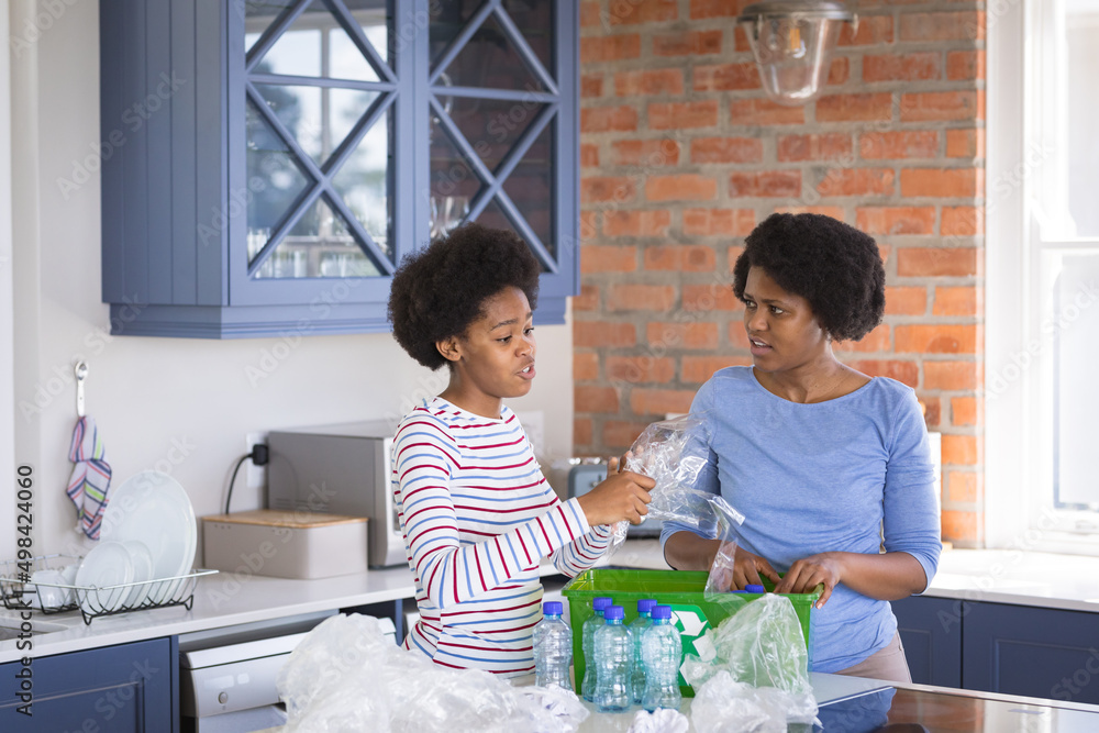 Mother talking with daughter while dumping plastic waste in garbage can ...