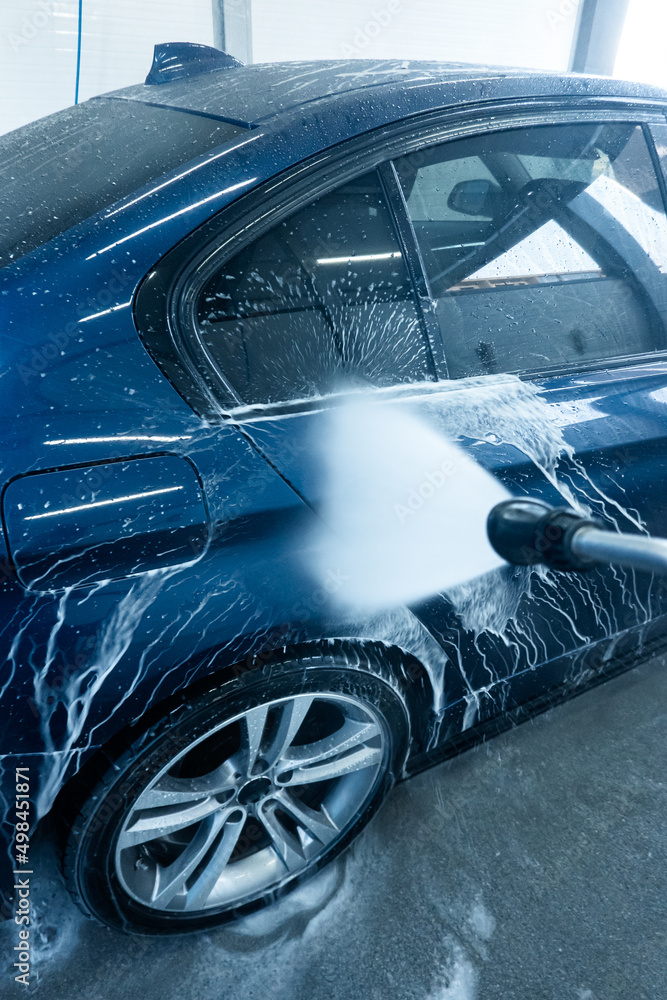 Self-service car wash station. Active foam is cleaning a dirty sedan ...