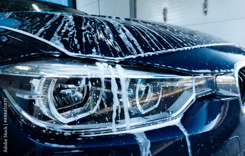 Self-service car wash station. Active foam is cleaning a dirty sedan ...