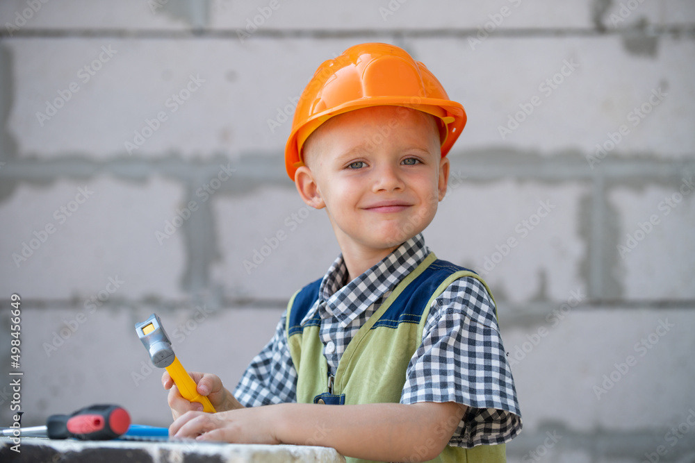 Cute little kid in builder helmet with repair tools on construction ...
