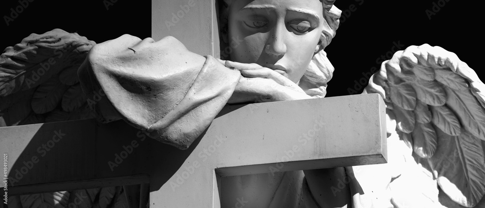 Ancient statue of angel with cross as symbol of Christianity, death and ...