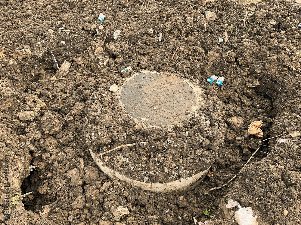 Newly installed sewage manhole in the back filled trench. Sewer manhole ...