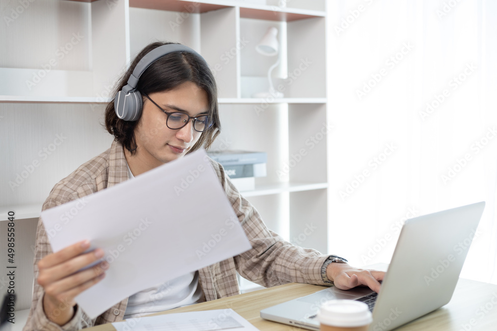 Male student is doing homework given by the teacher through the laptop's live performance system ...