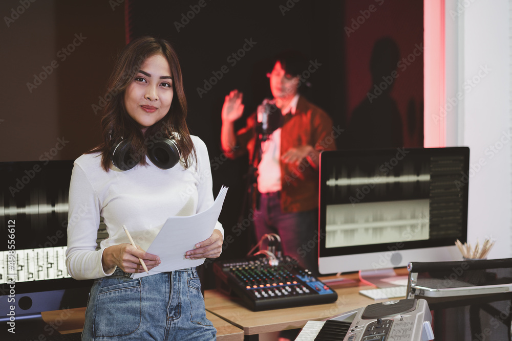 Asian couple singers in a recording studio using a studio microphone ...