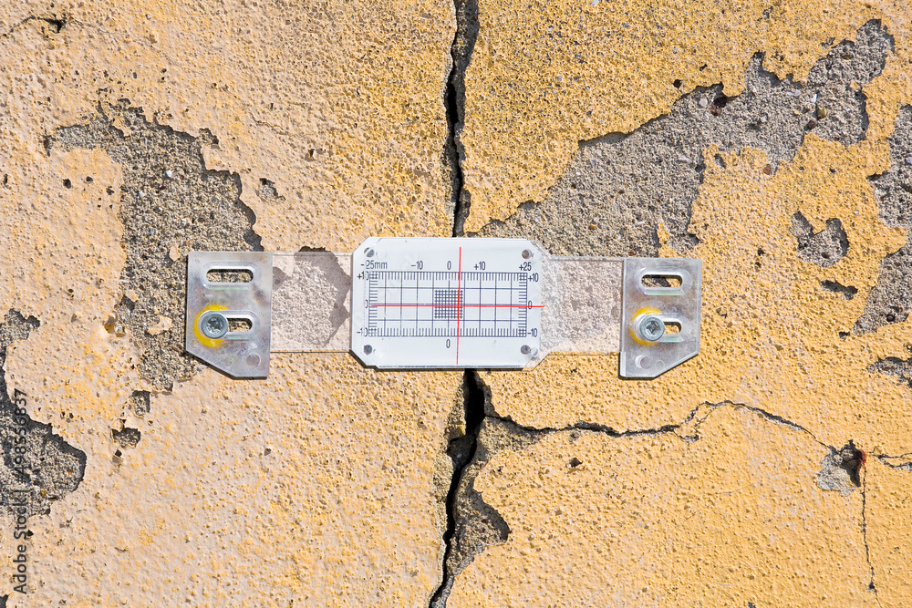 Deep crack in a damaged old plaster wall with plastic mechanical crack ...