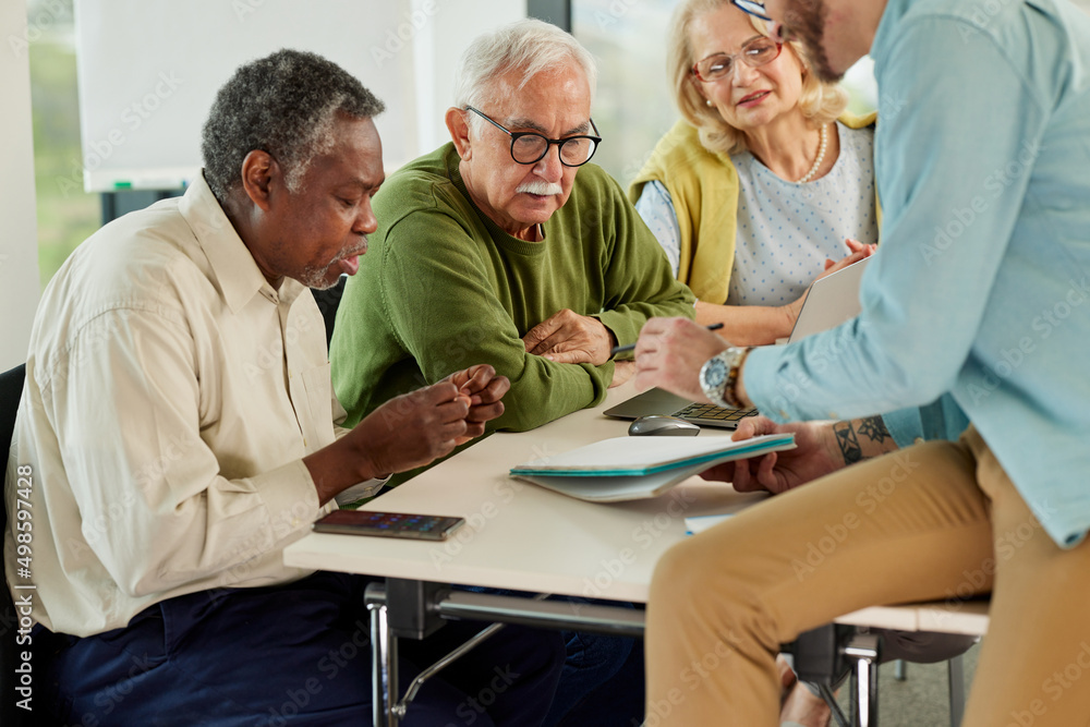 A multicultural group of elderly students listening to an explanation ...