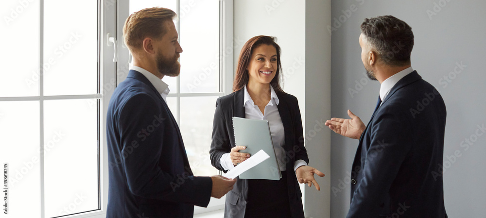 Team of three cheerful friends and coworkers talking during their break ...
