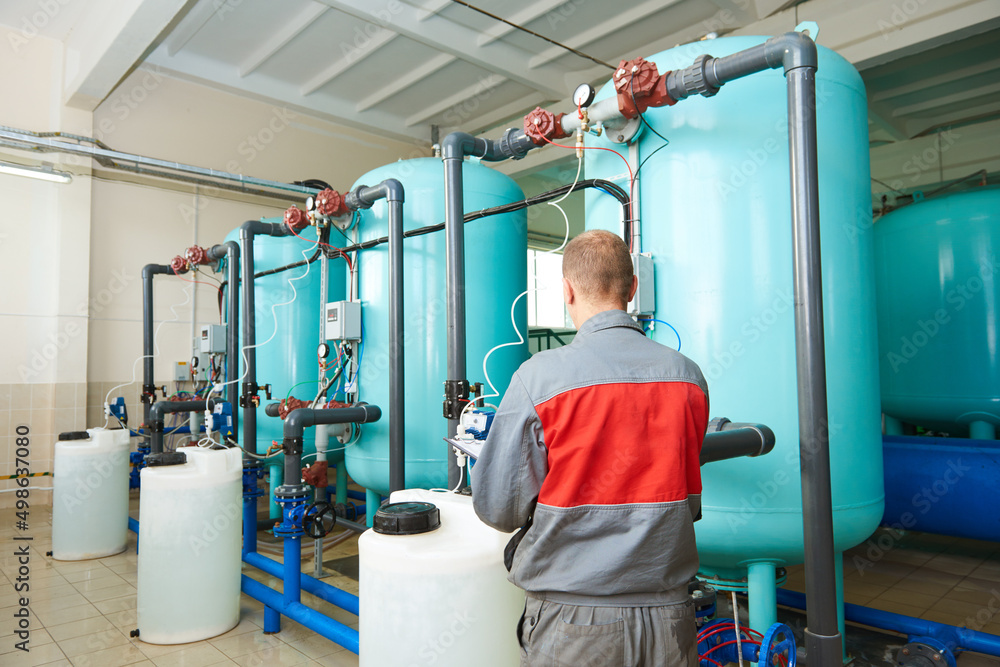 serviceman operating industrial water purification or filtration ...