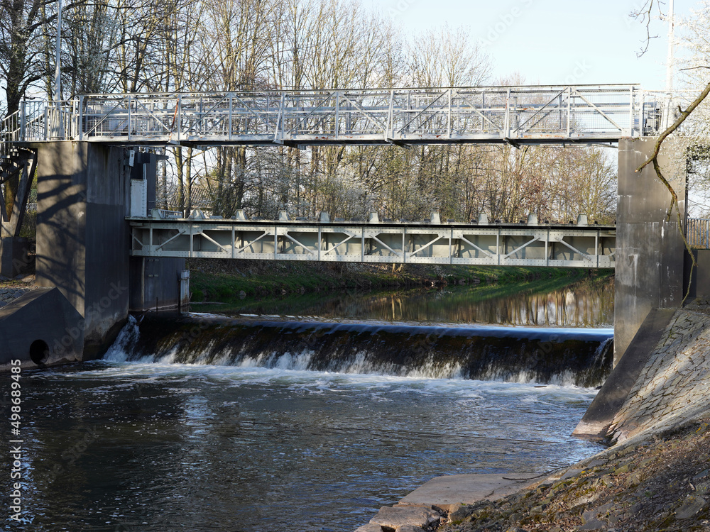 Big weir on the river. Water flows in a stream. We see the iron ...