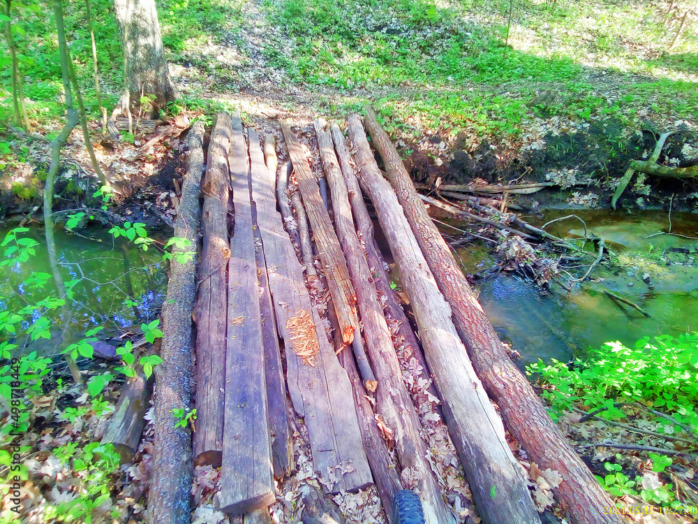 An old log bridge without a parapet over a small stream in the woods ...