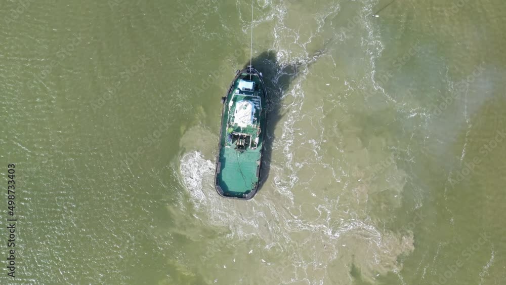 Aerial top down view of tugboat manoeuvring in shallow waters ...