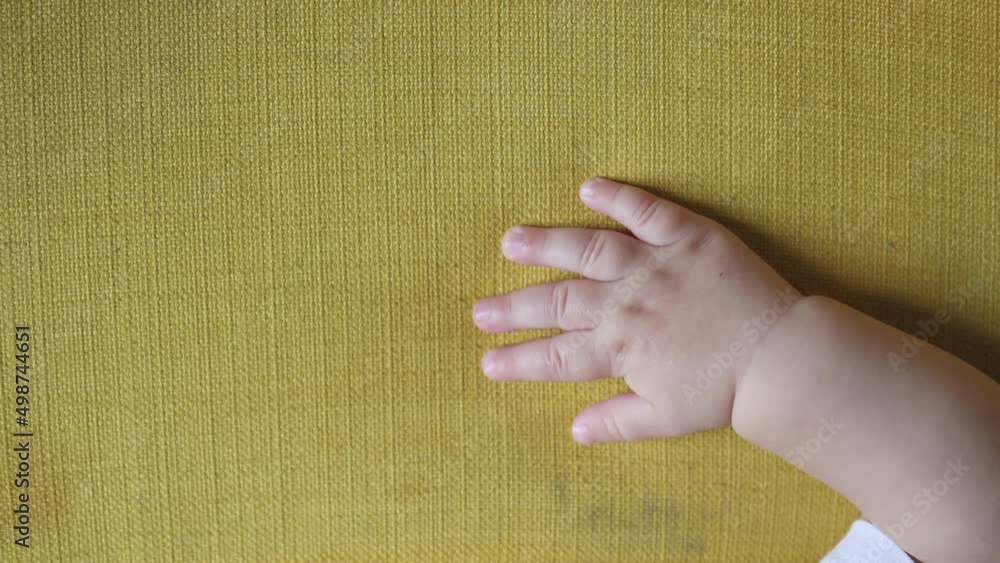 two tiny infant hands on yellow tissue background, baby fingers ...