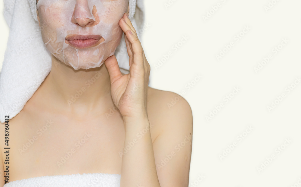 woman with towel on head and face mask sheet on the face is holding one ...