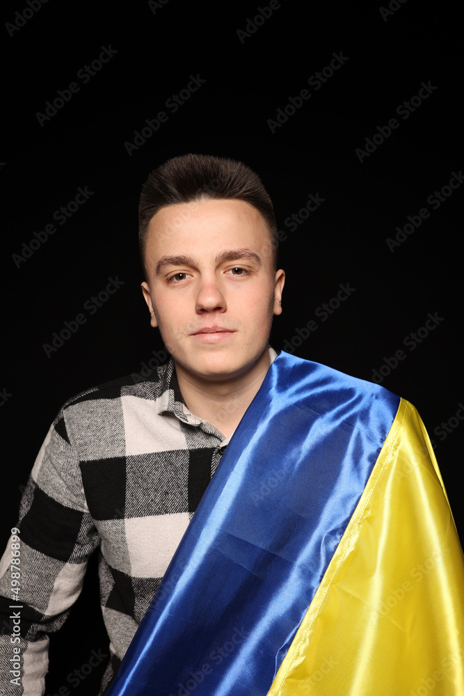 handsome Ukrainian man with the flag of Ukraine on a black background ...