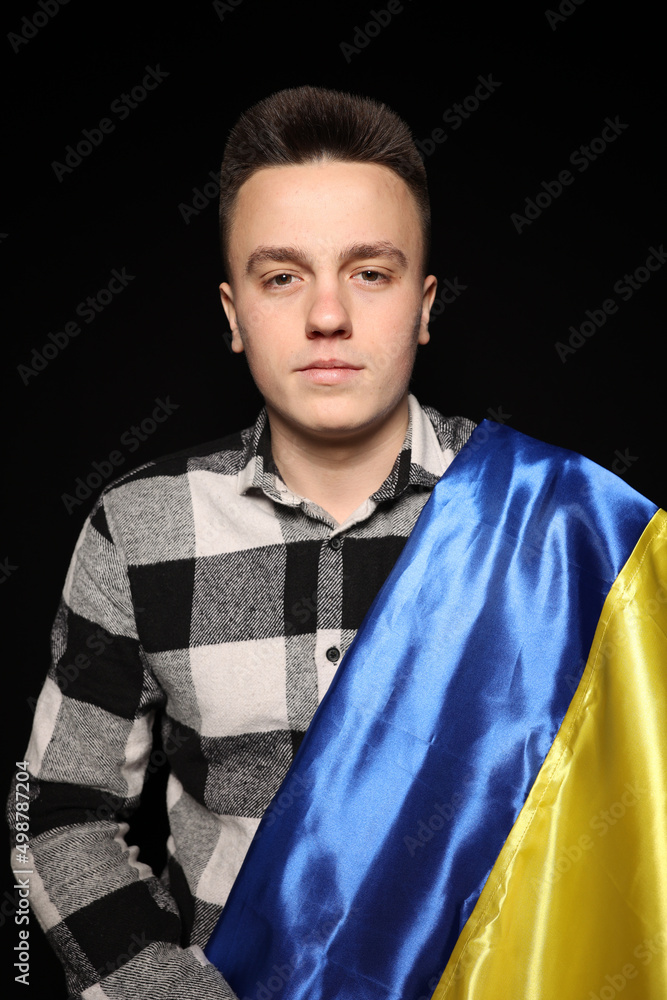 handsome Ukrainian man with the flag of Ukraine on a black background ...