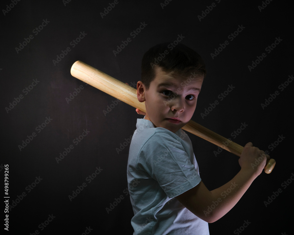 Angry boy on a black background with a bat in his hand.A European looks ...