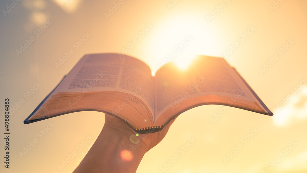 Hand holding bible up to the light Stock Photo | Adobe Stock