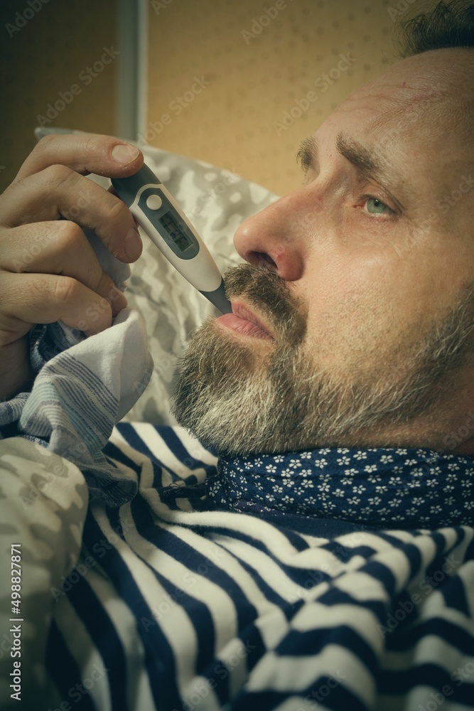 Mature sick man checking body temperature with thermometer Stock Photo ...