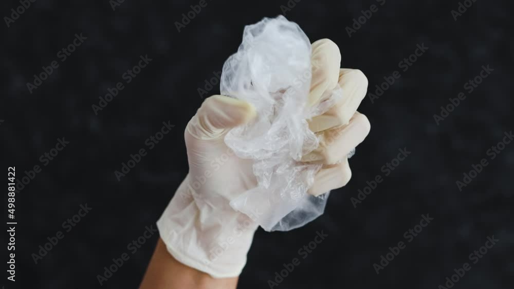 hand with glove picking up single-use plastic bag to be recycled ...