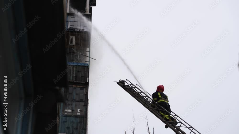 Firefighter on aerial ladder stairs extinguish a big fire in multi ...