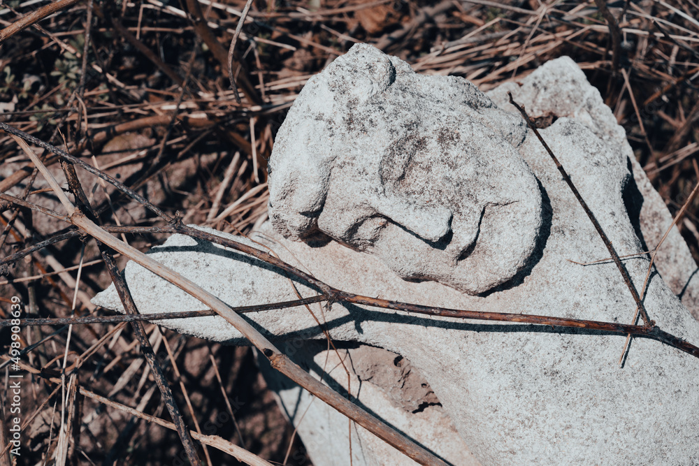 A piece of toppled stone crucifix sculpture on the ground at abandoned ...