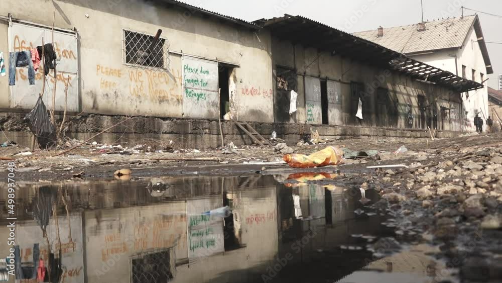 A dirty temporary refugee camp with lots of garbage on the ground, as ...