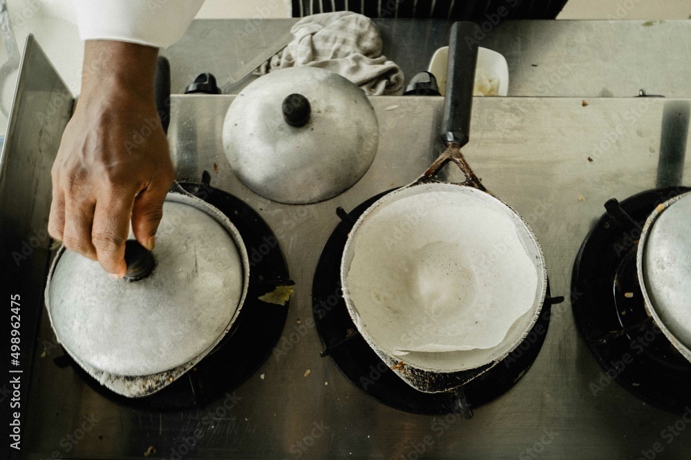 Hand of the chef opening the lid of the pot while making Sri lankan ...