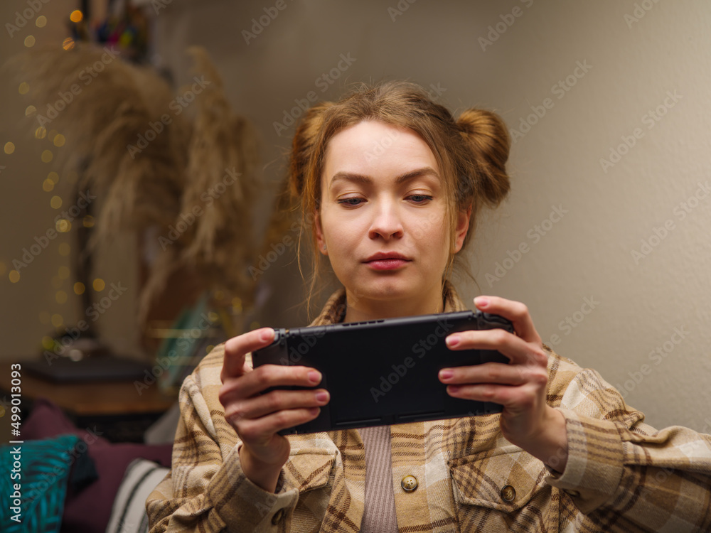 The gamer girl is looking at the screen of a portable game console ...