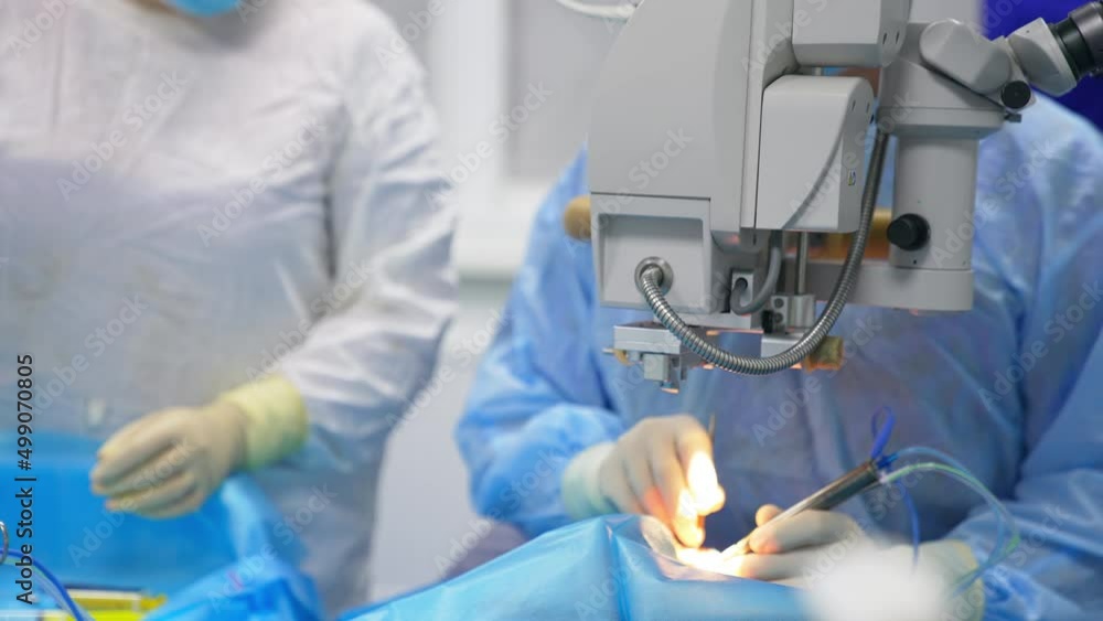Chief surgeon conducting eye surgery using electric devices. Nurse ...