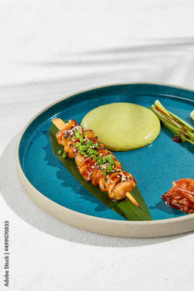 Squid yakitori in ceramic dish on white background. Japanese skewered ...